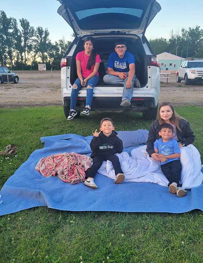 Families spread out on blankets in front of their vehicles, creating their own perfect viewing setup and comfort.