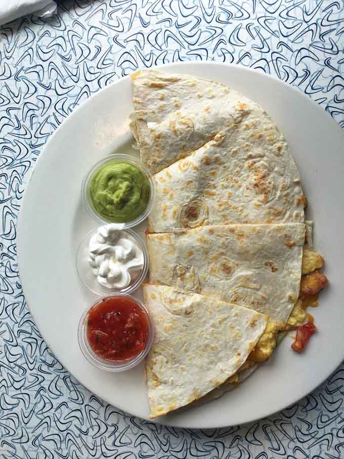 A breakfast quesadilla the size of a small country arrives with salsa, sour cream, and guacamole for maximum flavor.