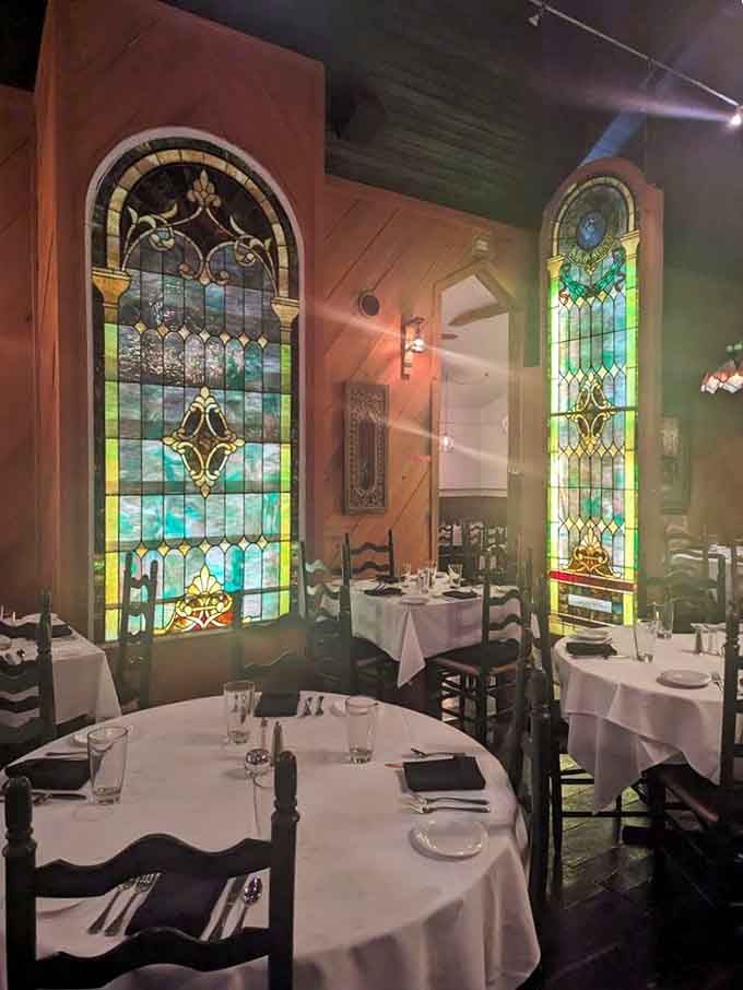 Stained glass windows cast a warm glow over intimate tables, creating an atmosphere that's both romantic and welcoming.