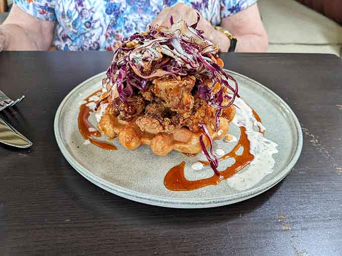 Chicken and waffles topped with cabbage slaw, proving breakfast-for-lunch never looked this good or this towering.