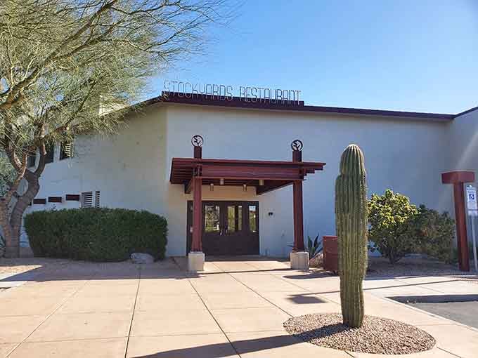 Desert landscaping frames the entrance where that iconic rooftop sign promises authentic Western steakhouse hospitality awaits within.