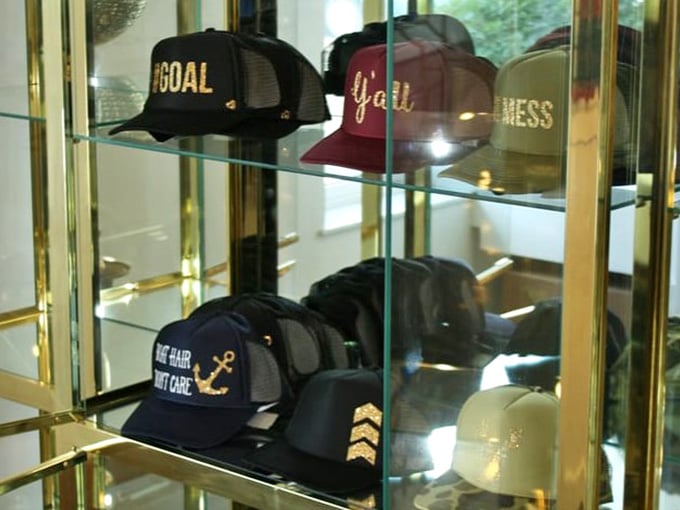Statement caps in a gold-trimmed display case prove even casual accessories get the museum treatment when they carry the right labels and attitude.