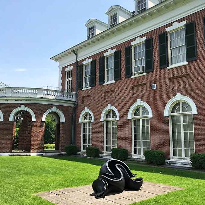 Modern sculpture creates striking contrast against traditional architecture, inviting contemplation on the sunlit lawn.