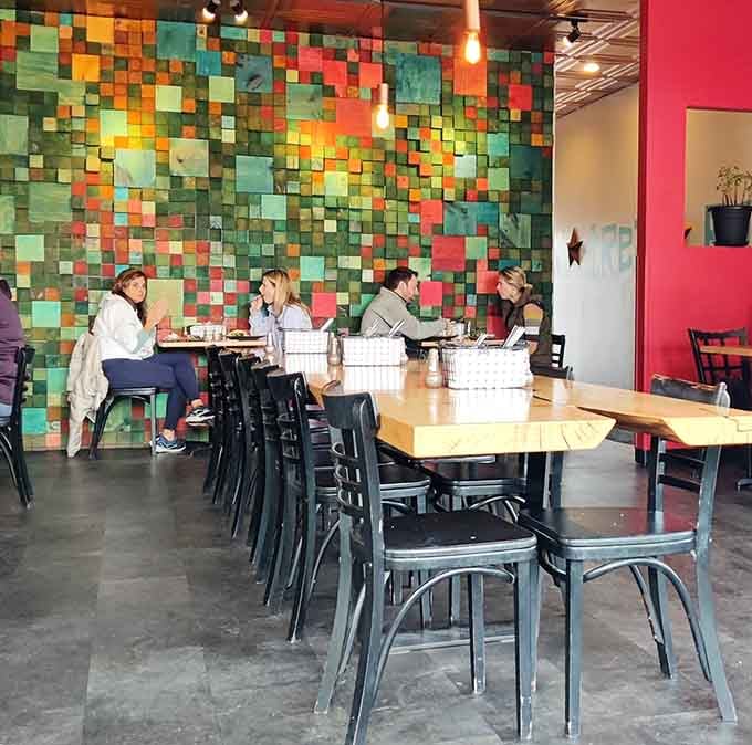 Happy diners gathered around that colorful wall prove that great food brings people together better than any social media algorithm ever could.