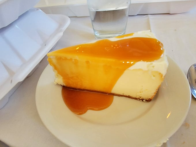 Cheesecake with golden sauce cascading down its sides, smooth and creamy perfection on a plate.