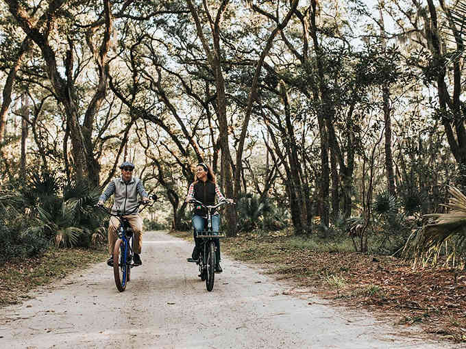 Shaded bike paths wind through maritime forests where the only traffic jams involve stopping to watch deer cross your path.