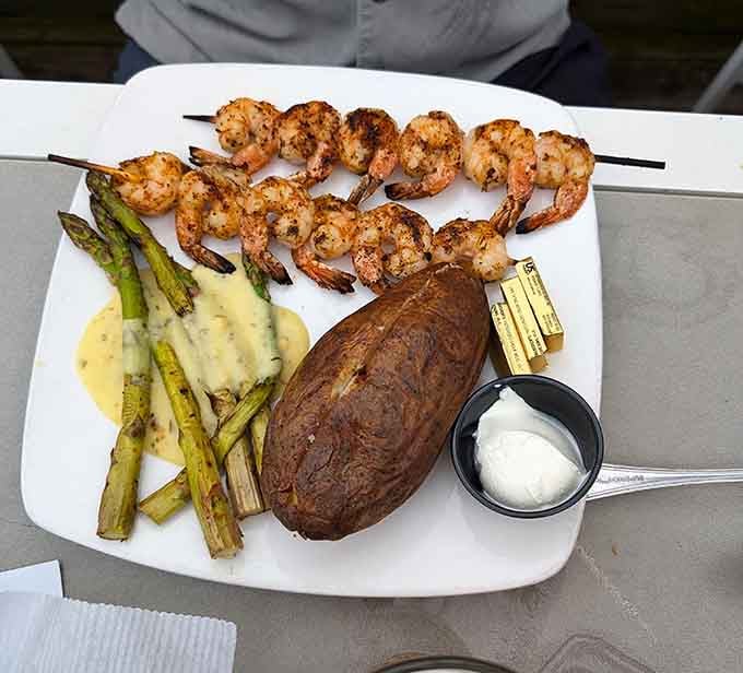 Grilled shrimp skewers with asparagus and baked potato bring surf and turf together in perfect harmony.