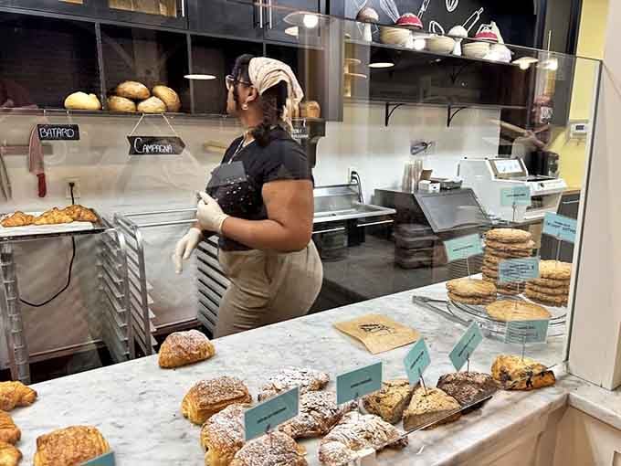 Behind that glass, skilled hands transform flour and butter into edible art while you watch the magic unfold.