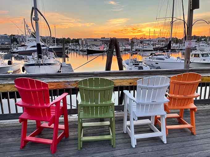 Colorful Adirondack chairs facing the marina at sunset, where the view rivals the food for your attention and usually wins.