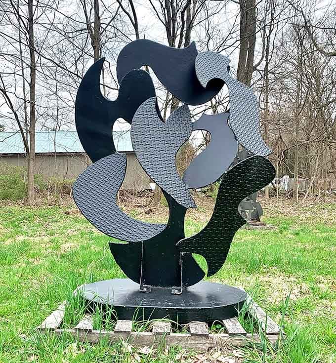 Marvel at the grace of this large, curvilinear steel work, offering a sophisticated contrast to the lush forest backdrop.