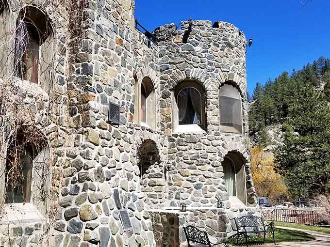 The castle tower stands against blue Colorado skies, looking weathered and timeless despite being a modern creation.