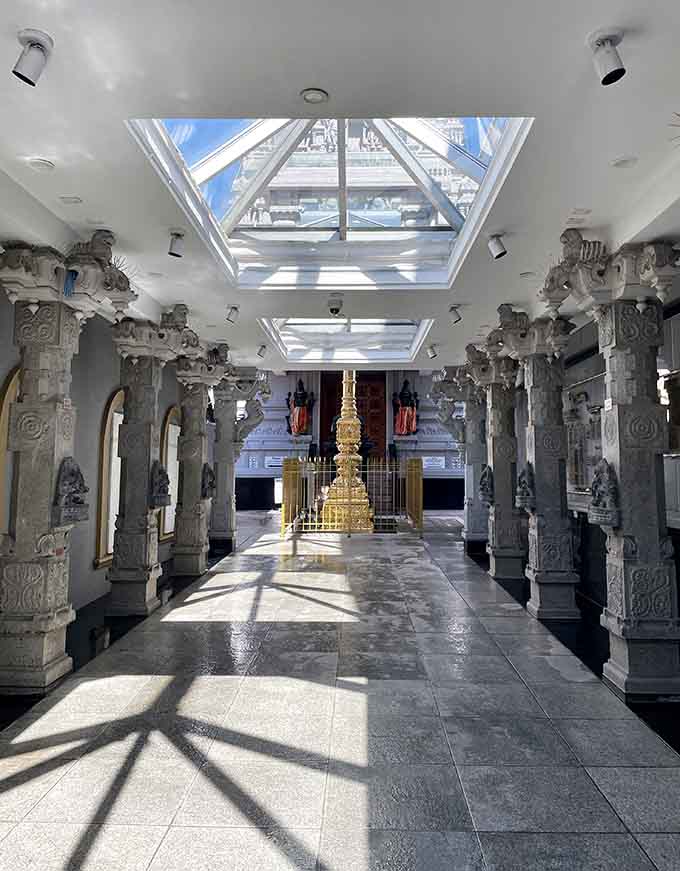 The temple's interior hallway showcases stunning architecture with intricately carved pillars that make the journey downstairs even more special.