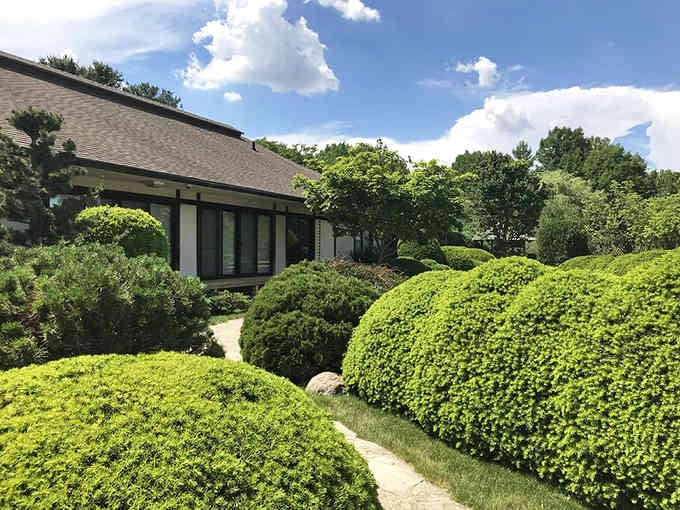 The traditional Japanese house sits nestled among perfectly manicured shrubs like a postcard from another world.
