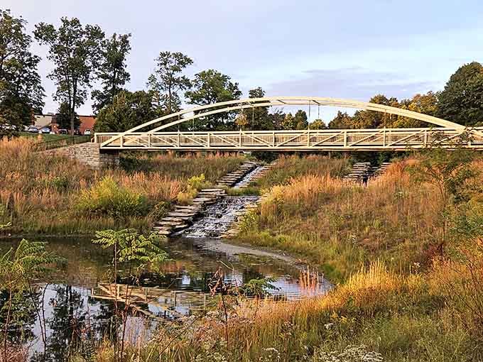 The modern bridge arches gracefully over native grasses, blending contemporary design with natural beauty that actually works here.
