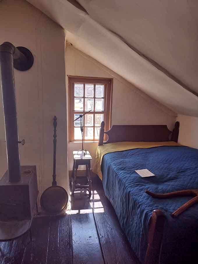 Slanted ceilings and a blue coverlet create an attic bedroom where colonial dreams were dreamed under hand-hewn beams.