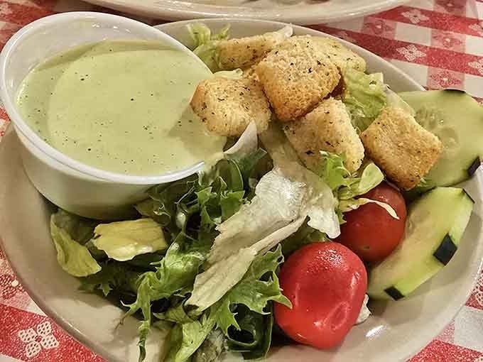 Fresh greens with homemade dressing offer a lighter option, though we both know you're saving room for pudding.