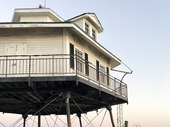 The wraparound gallery and weathered siding tell stories of decades spent standing guard over these waters.