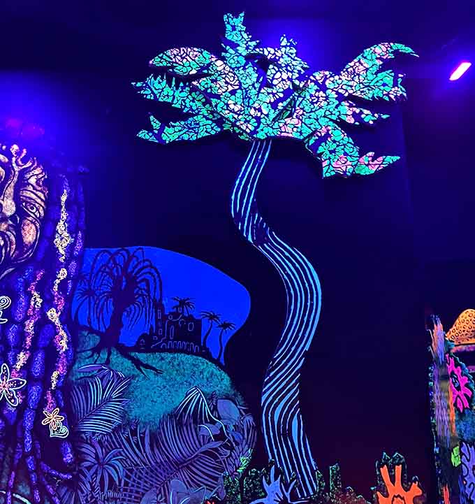 A glowing tree stretches across the wall, adding a dreamy backdrop to neon-lit mini golf adventures.