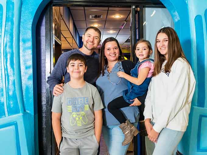 Families gather at the glowing entrance, ready to create memories in a place where normal lighting rules don't apply.