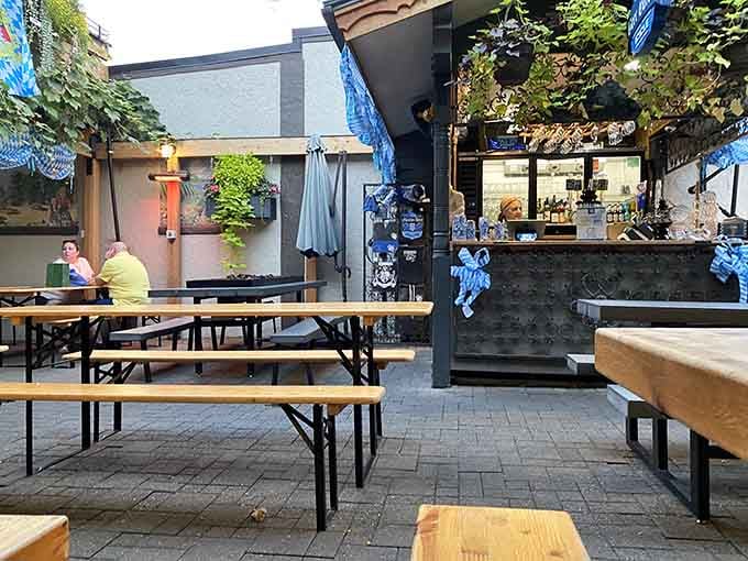 Biergarten seating under Bavarian banners where communal tables turn meals into celebrations, rain or shine be darned.