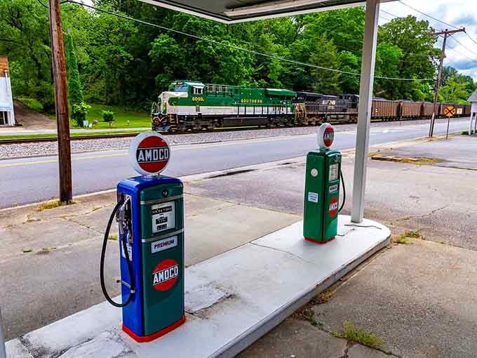 Vintage gas pumps and passing trains create a scene straight from simpler times, when life moved slower and that was perfectly fine.