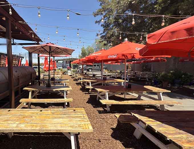 Picnic tables under string lights and red umbrellas make outdoor dining feel like a backyard barbecue with seriously upgraded food.