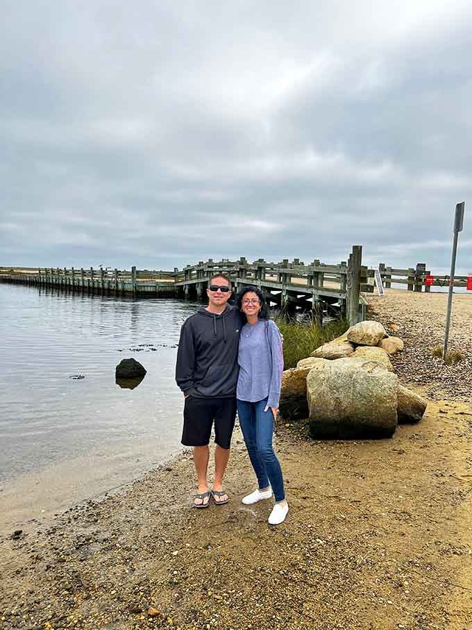 Smiling visitors pause by the weathered dock, capturing proof they made the journey to this spectacular slice of coastal heaven.