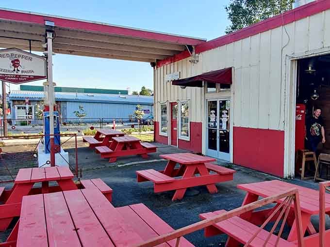 Red picnic tables outside the pizzeria invite you to slow down and remember what eating together means.
