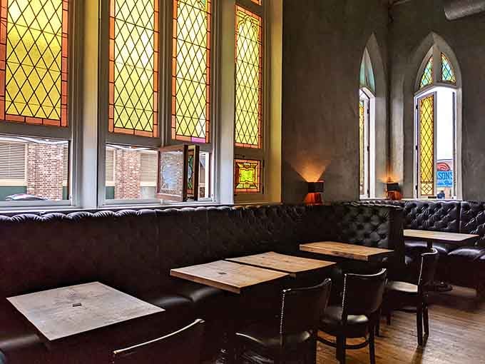 Golden afternoon light streams through diamond-paned windows, illuminating booths where guests savor both food and architectural beauty simultaneously.