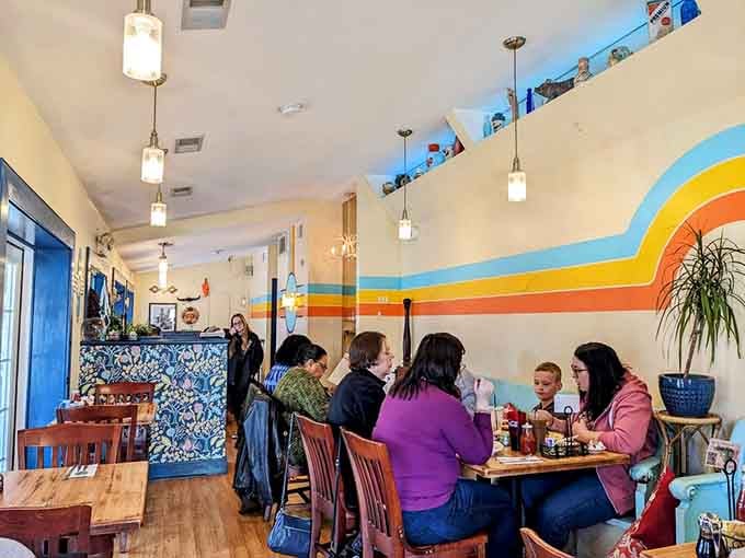 Happy diners beneath that glorious sunburst mural, living their best breakfast lives without a single regret visible.