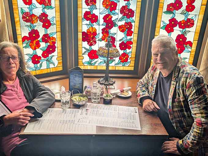 Happy diners enjoying their meal beneath stained glass windows, living their best German restaurant life in Connecticut.