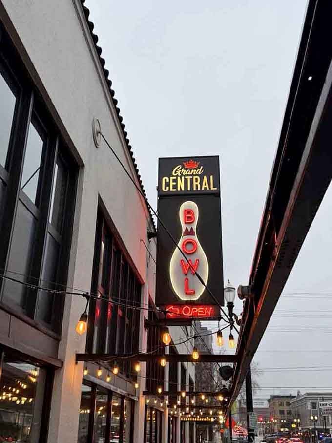 String lights frame the iconic bowling pin sign on a cloudy day, inviting you inside for warmth and wonder.