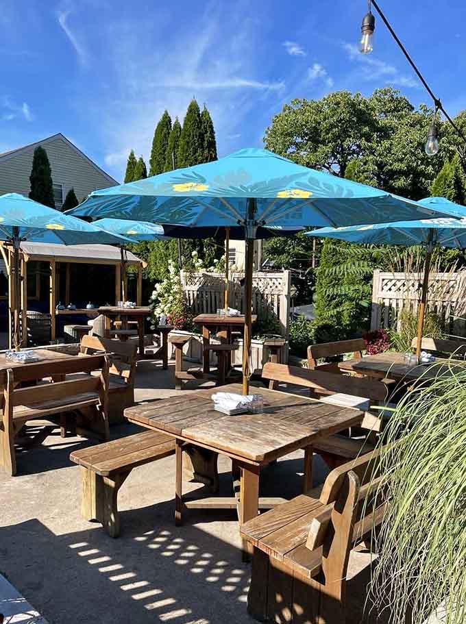 Turquoise umbrellas shading wooden picnic tables under blue skies make alfresco dining feel like a mini vacation right here.