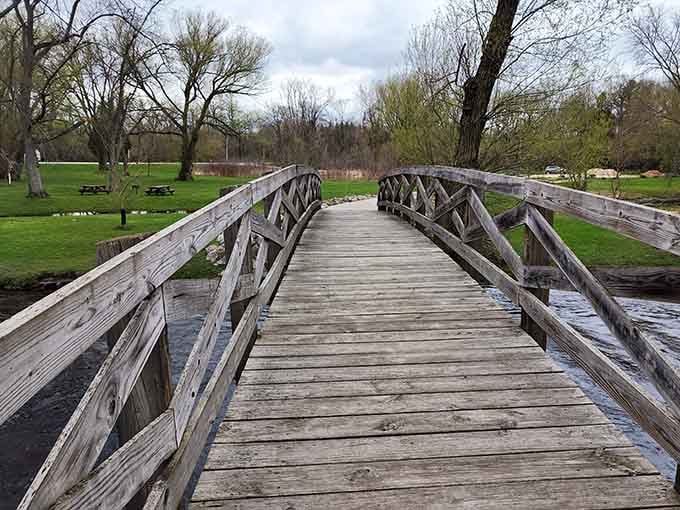 The wooden walkway leads you across the creek, each plank whispering stories of countless footsteps before yours.