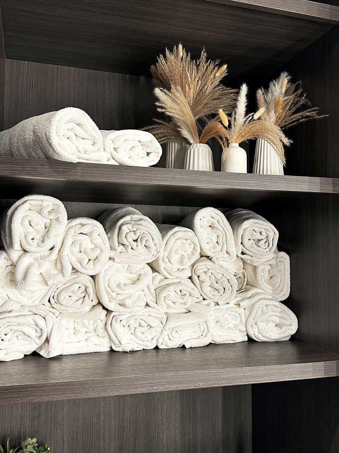 Fluffy white towels stacked like clouds promise the kind of softness that makes you question your home linens.