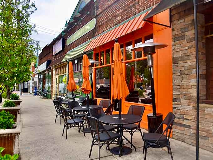 Sidewalk seating under orange umbrellas where neighborhood charm meets exceptional breakfast in perfect harmony.
