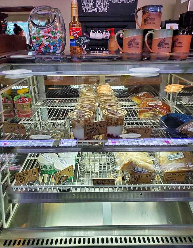 The pastry case displays fresh treats like precious jewels, each one calling your name louder than necessary.