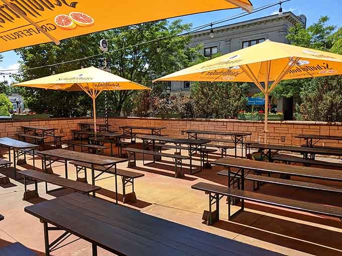 The outdoor biergarten awaits under sunny yellow umbrellas, ready for warm evenings filled with laughter and lagers.