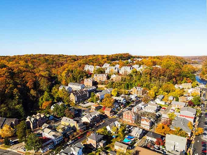 Aerial view revealing a town nestled in autumn foliage like a secret hideaway from the modern world.