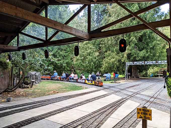 A full train departs the station beneath working signals, carrying passengers on a journey that's surprisingly delightful.