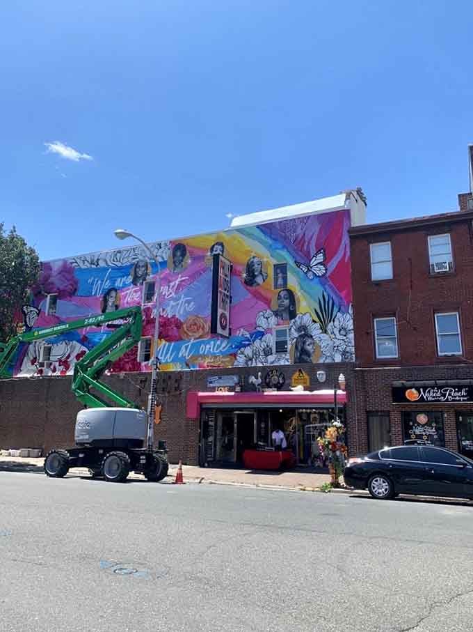 The exterior mural transforms an entire city block into an outdoor art gallery celebrating community and pride.