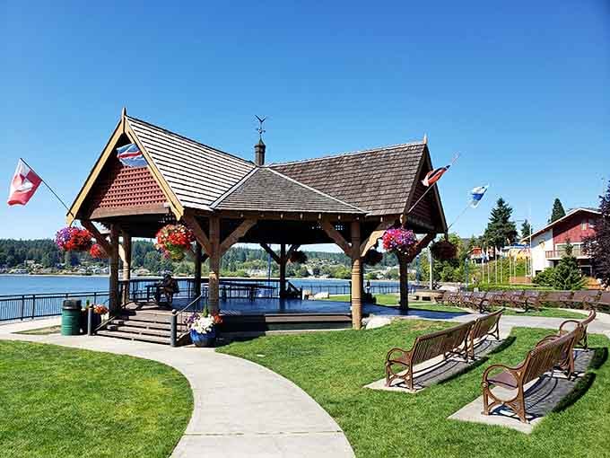Hanging flower baskets frame the waterfront pavilion where Liberty Bay sparkles beyond benches perfect for contemplative afternoon sitting.