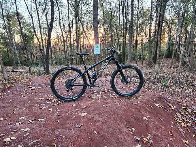 A solitary bike rests on russet clay at sunset, patiently waiting for its next thrilling descent through the woods.