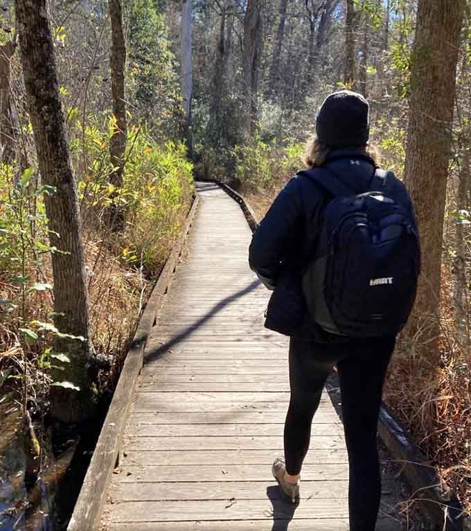 A hiker ventures down the boardwalk into golden light, proving that sometimes the best destinations are surprisingly close to home.