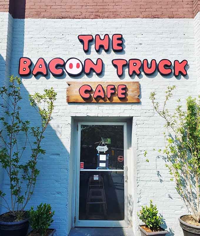 The entrance beckons with that cheerful signage, flanked by potted plants that add life to this bacon lover's paradise.