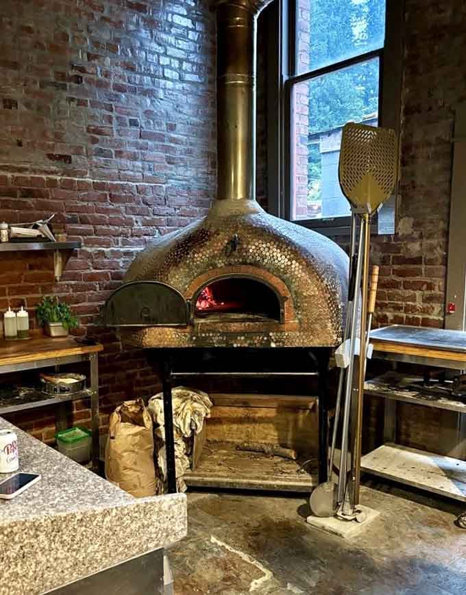 That gleaming wood-fired oven works overtime turning sourdough into crispy, chewy, absolutely perfect pizza crust every single time.