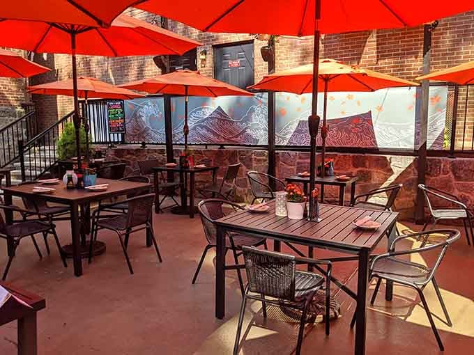 The spacious patio with its cheerful red umbrellas transforms an ordinary meal into a delightful alfresco experience.
