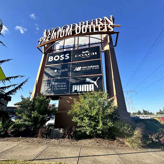 The towering sign announces premium brands at outlet prices, visible from the highway like a beacon of hope.