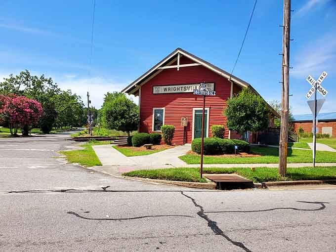 The old depot stands red and proud at the crossing, a testament to when trains connected small towns.