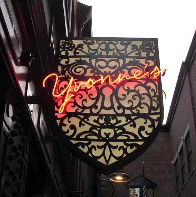 The glowing Yvonne's sign against ornate metalwork announces you've found the place where history meets exceptional modern dining.